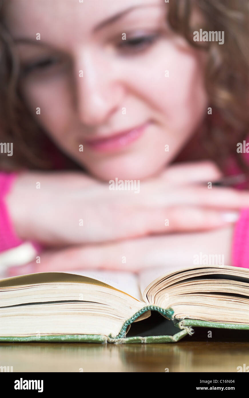 Pretty female is reading book. Primary focus is on book Stock Photo - Alamy