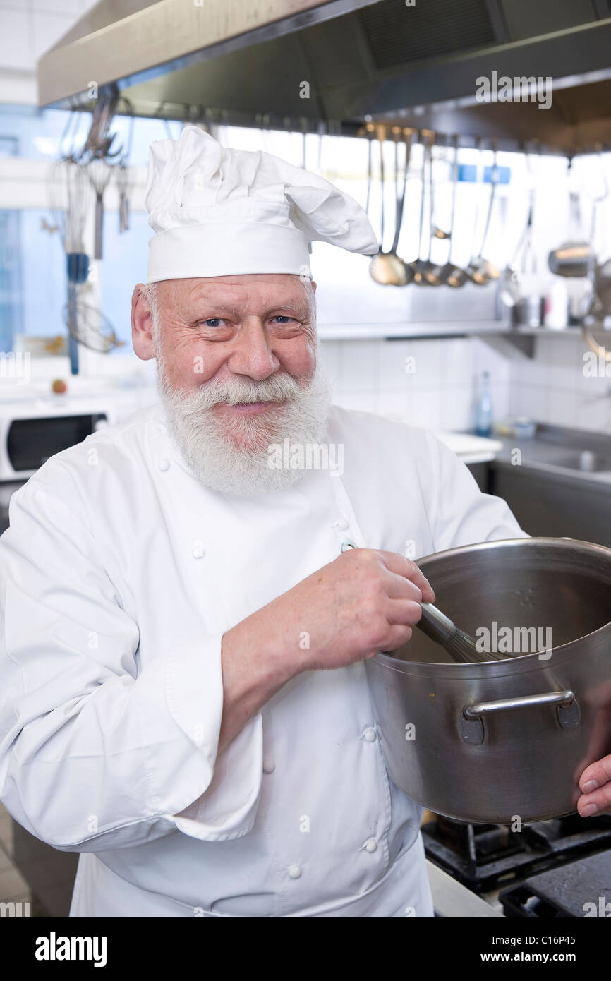 Cook wearing a chef's hat, stirring a pot Stock Photo - Alamy
