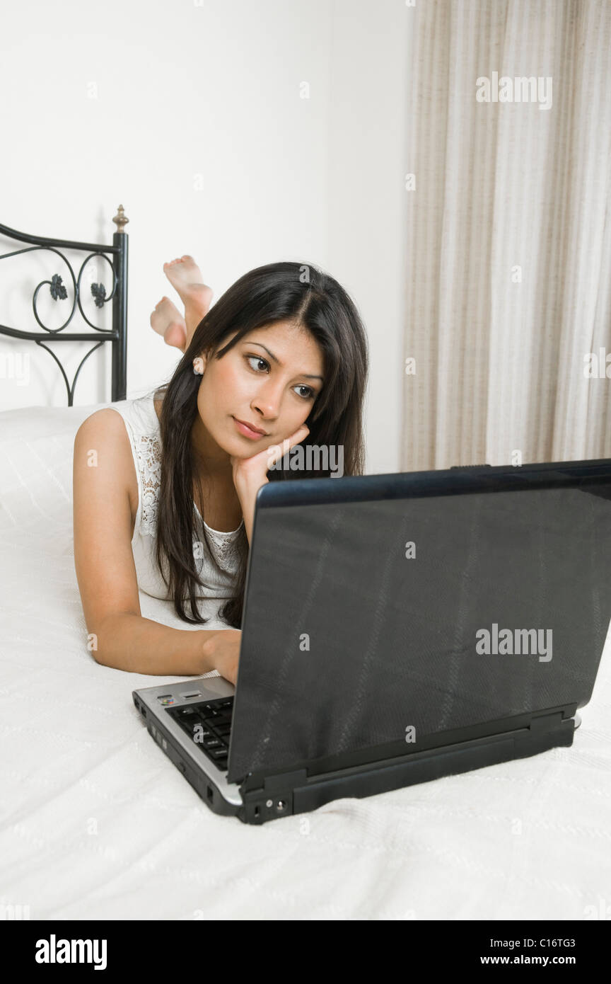 Woman using a laptop on the bed Stock Photo - Alamy