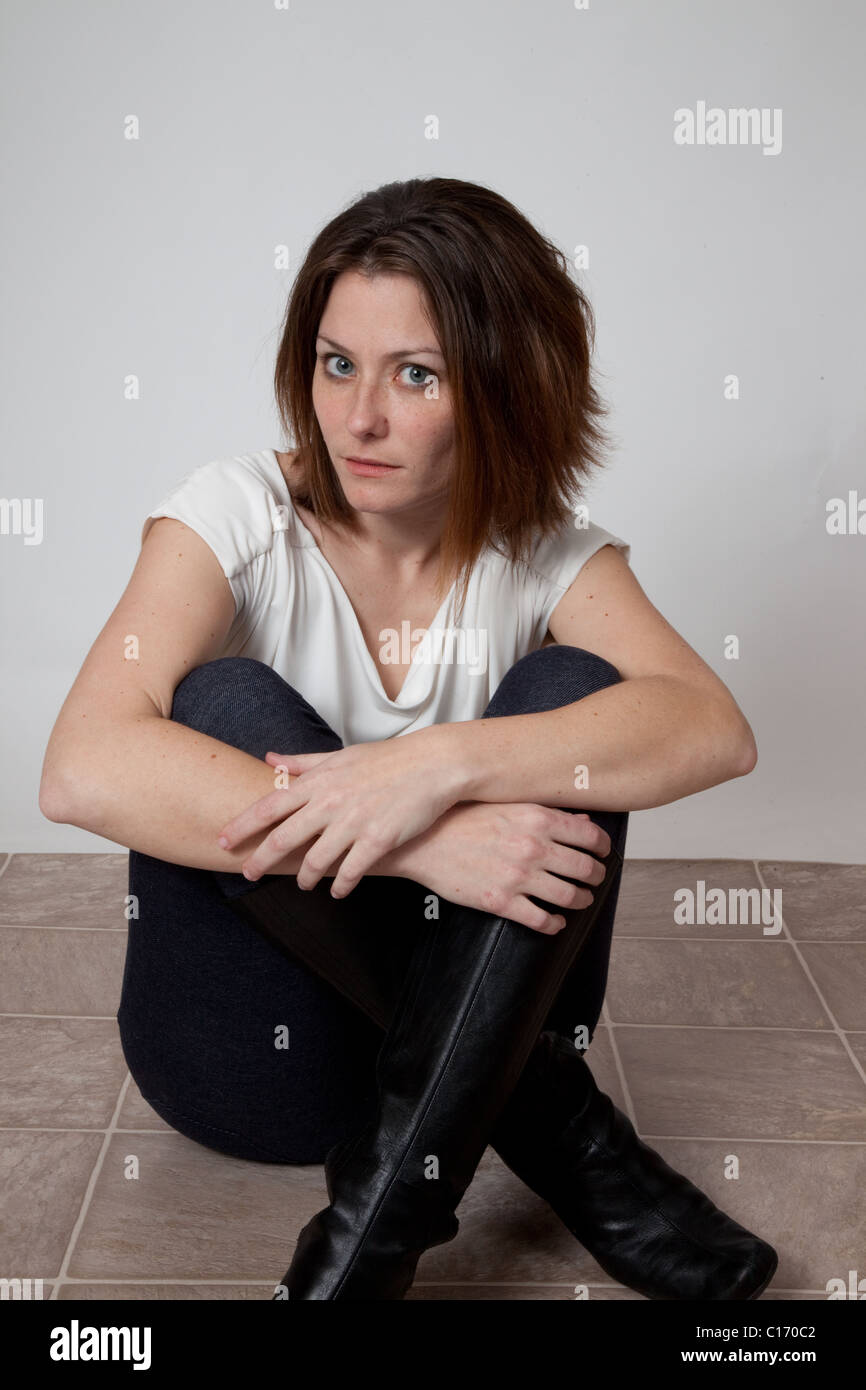 Pretty woman sitting on floor with her arms around her knees, and a ...