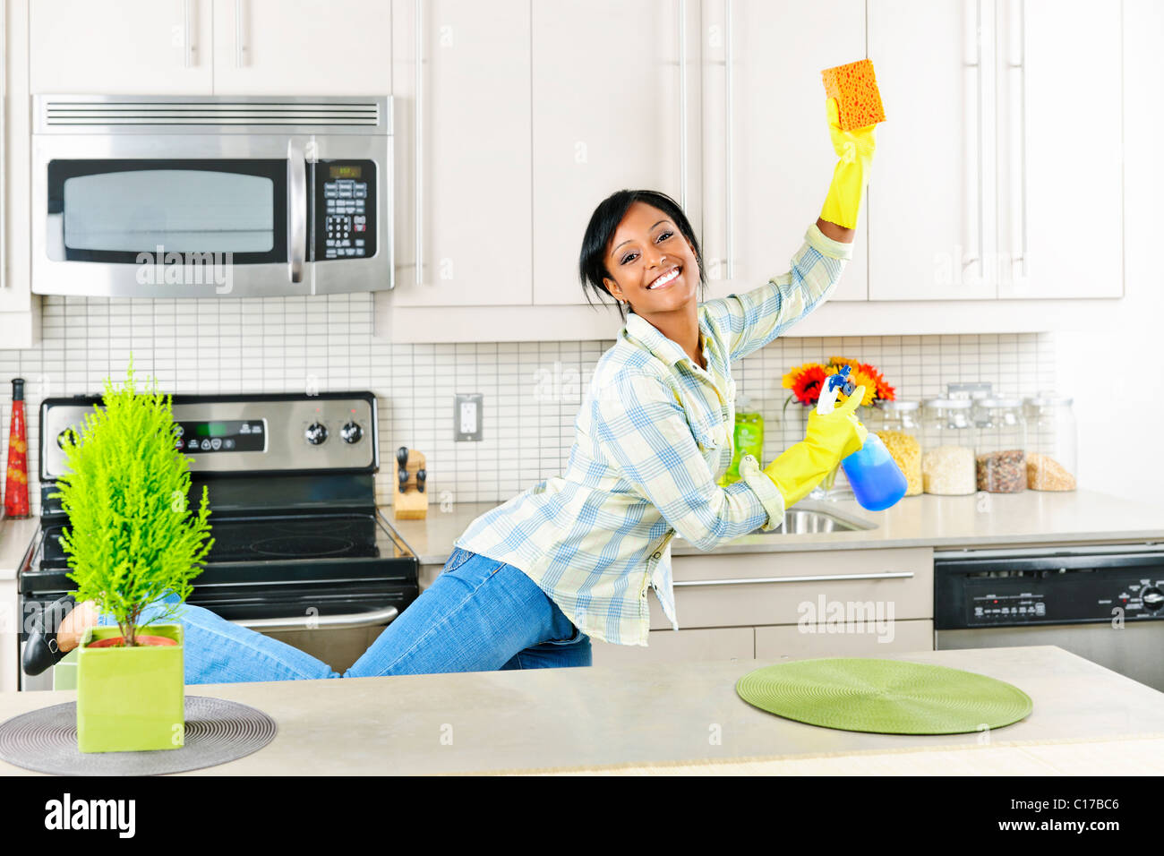 Smiling young black woman dancing and enjoying cleaning kitchen Stock ...
