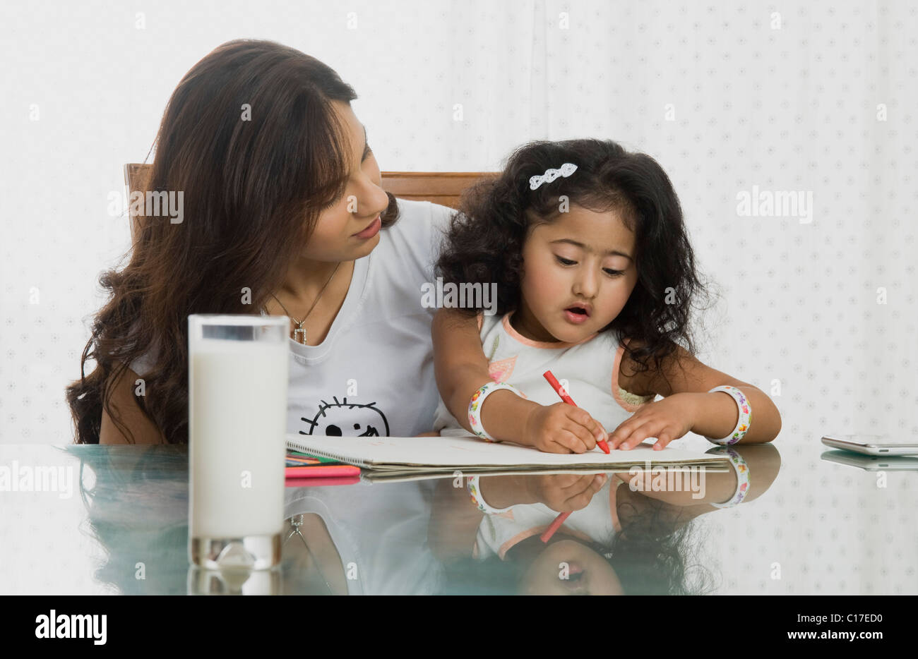 Close-up of a girl drawing with her mother at the dining table Stock ...