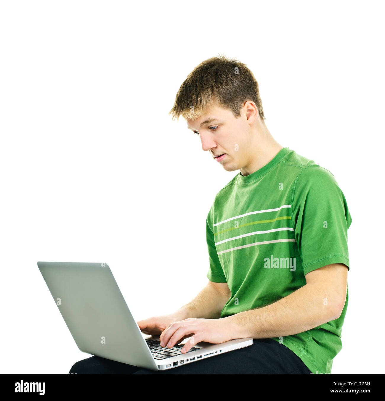 Serious young man sitting with laptop computer isolated on white ...