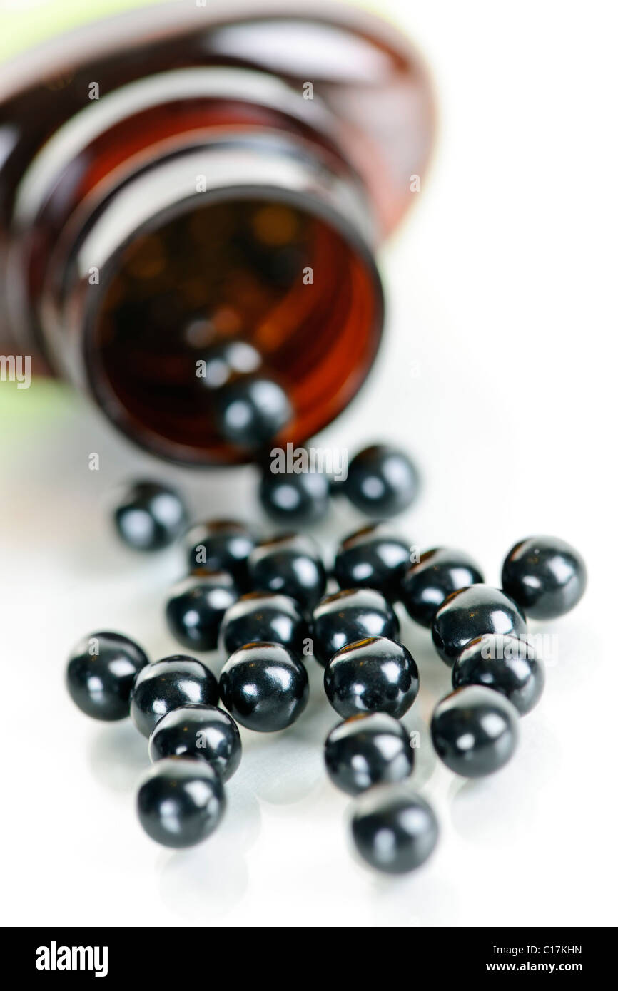 Traditional chinese herbal medicine pills spilling from bottle on white ...