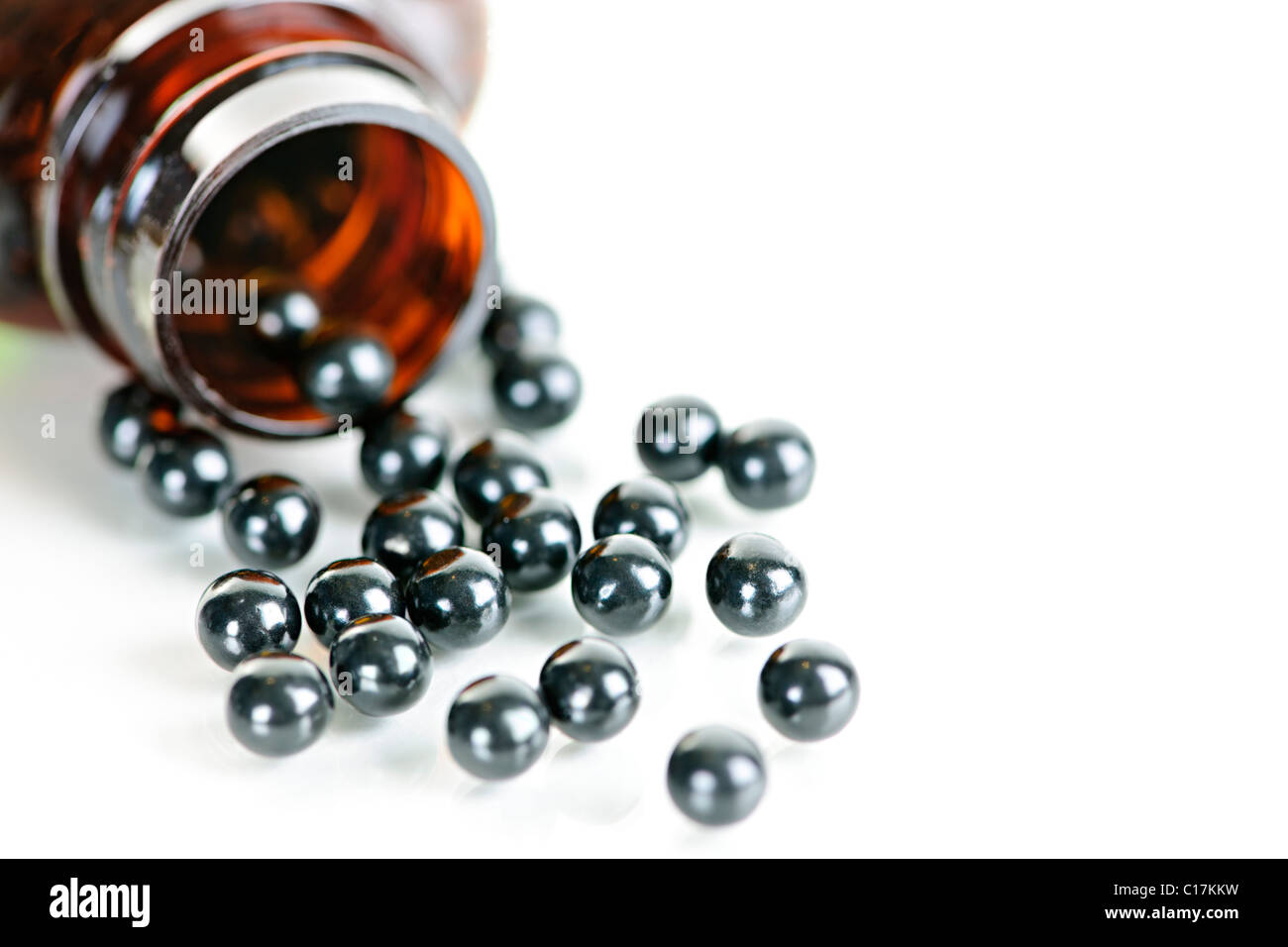Traditional chinese herbal medicine pills spilling from bottle on white ...