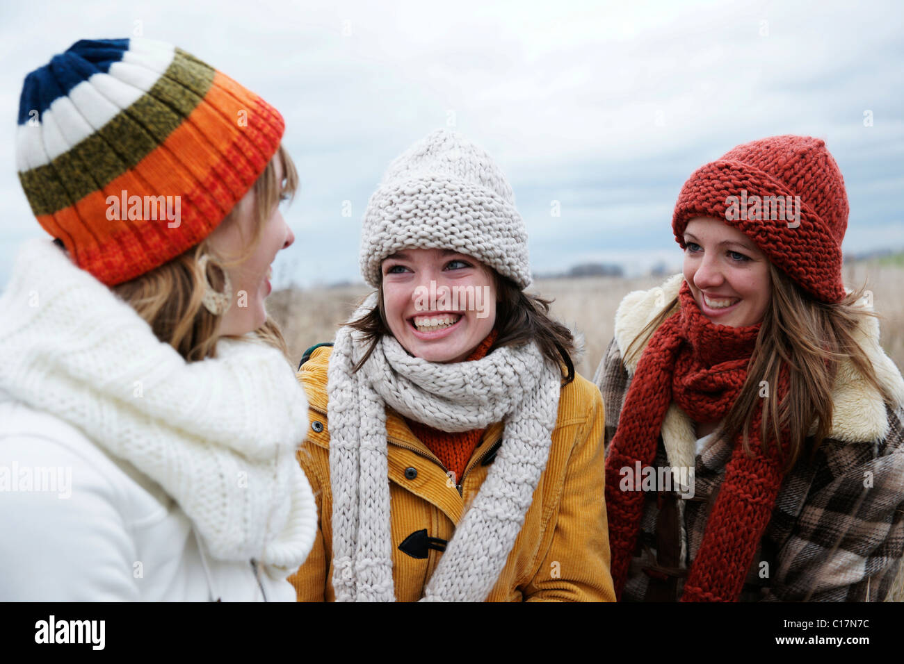 Three laughing teenage girls wearing hats and scarfs Stock Photo - Alamy