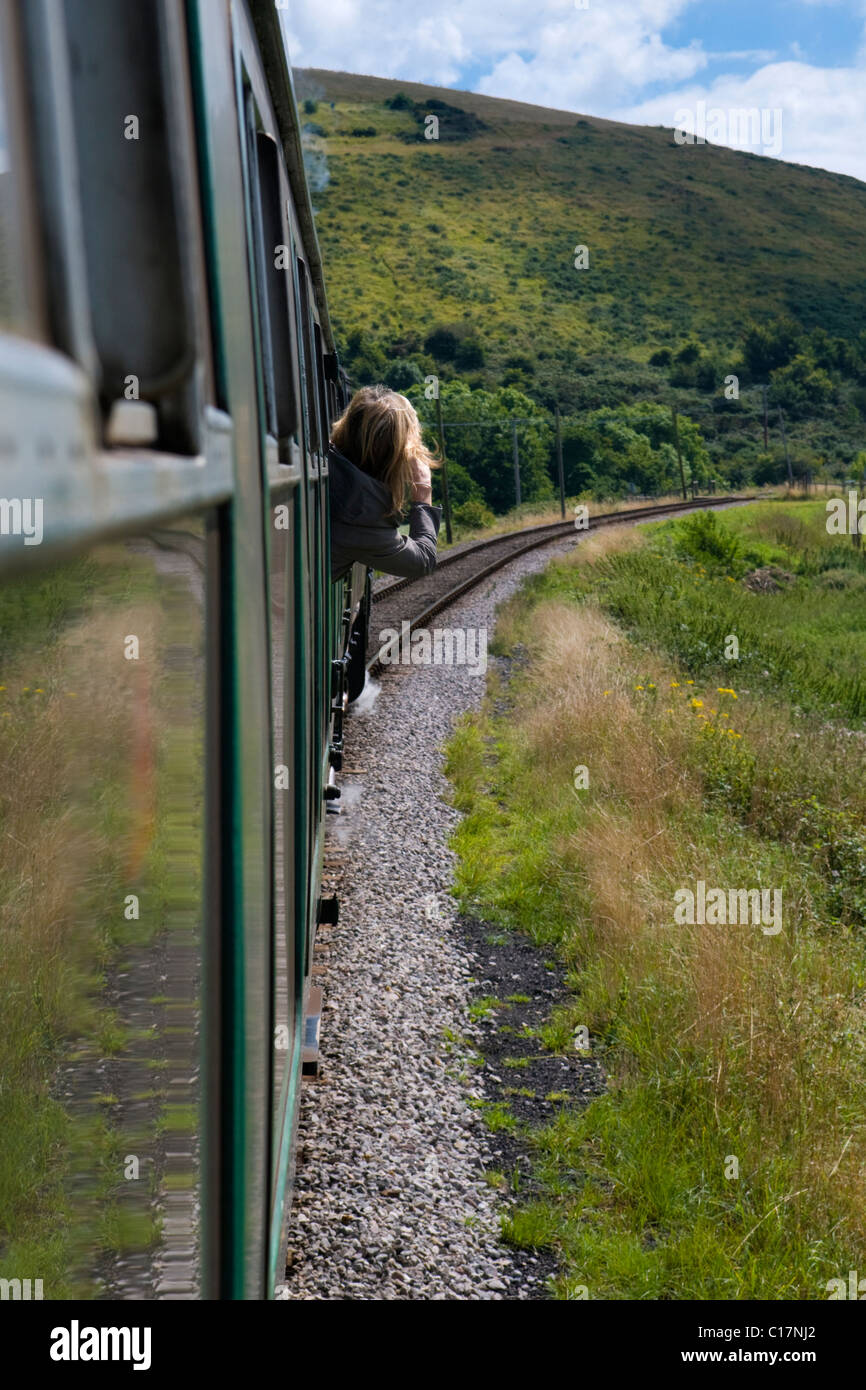 A woman leaning out of a train window to admire the view as it travels ...