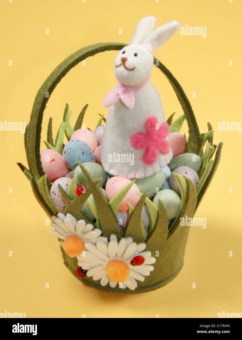 Green Easter Basket with Felt Bunny and Eggs on Yellow Background Stock ...