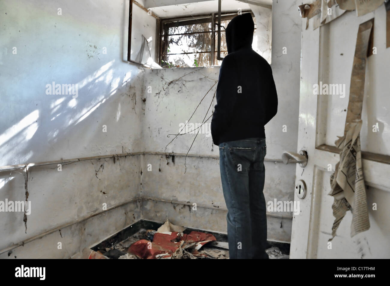 Hooded man looking through the broken window of abandoned house Stock ...