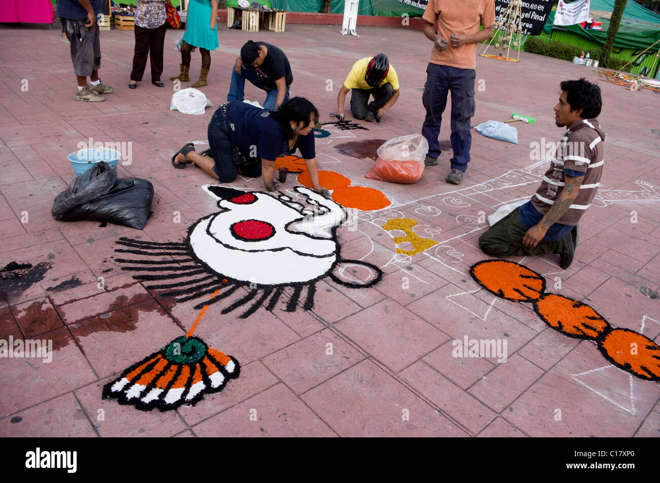 Aztec dance group drawing a figure with colored sand on the day of the ...