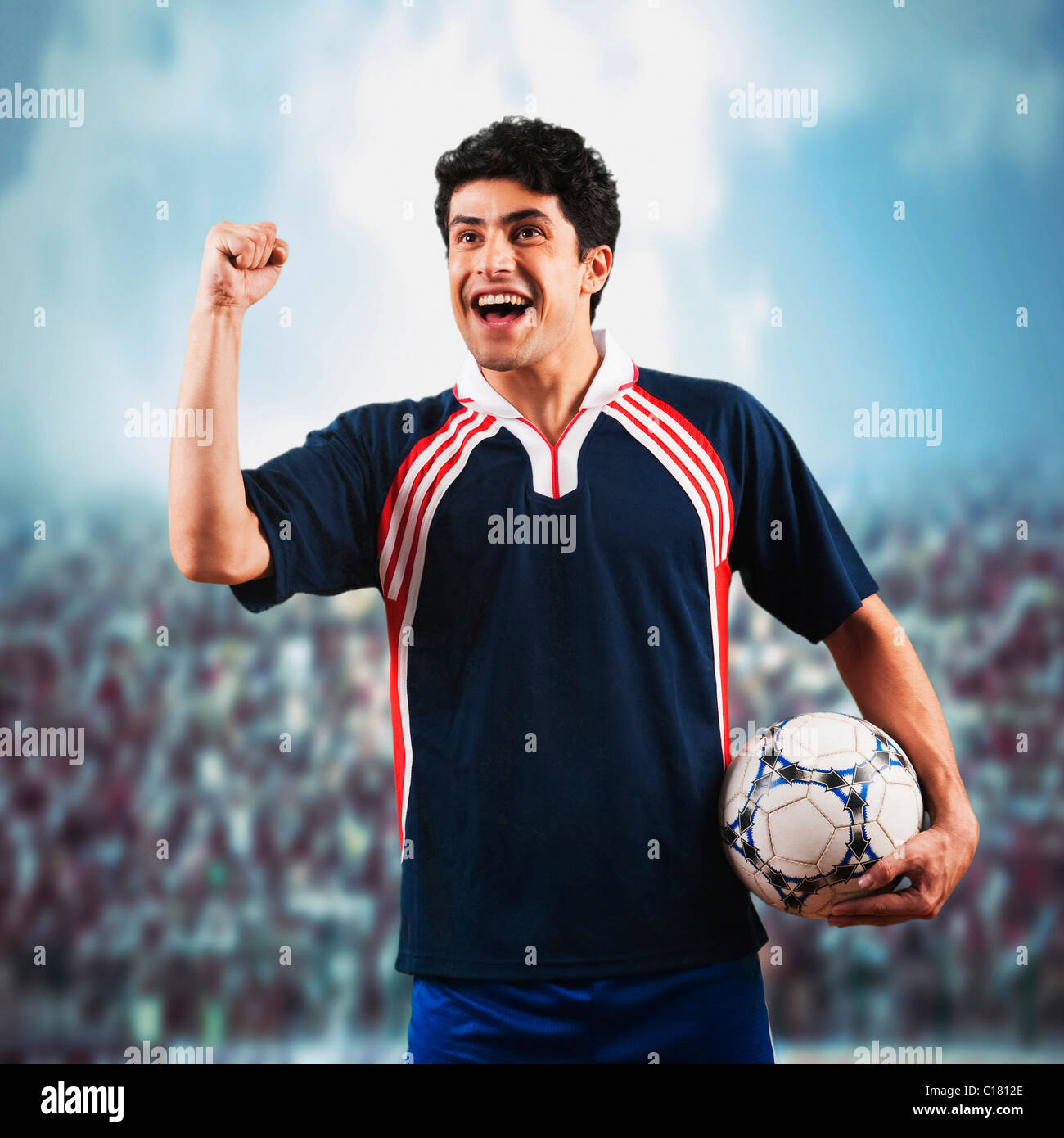 Soccer player holding a soccer ball and clenching fist Stock Photo - Alamy