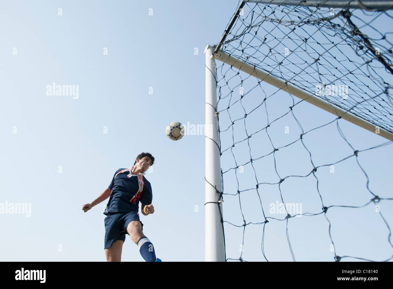 Soccer player heading a soccer ball in the net Stock Photo - Alamy