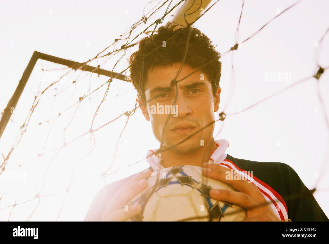 Soccer player holding a soccer ball behind the net Stock Photo - Alamy