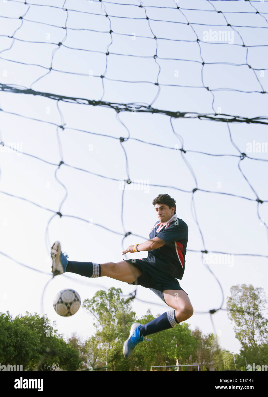 Soccer player kicking a soccer ball in the net Stock Photo - Alamy