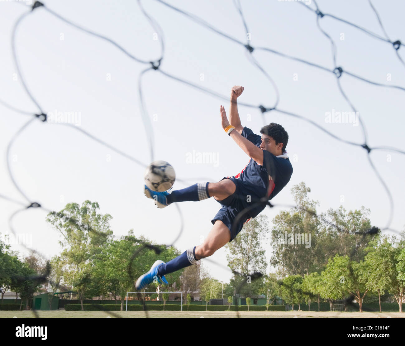 Soccer player kicking a soccer ball in the net Stock Photo - Alamy