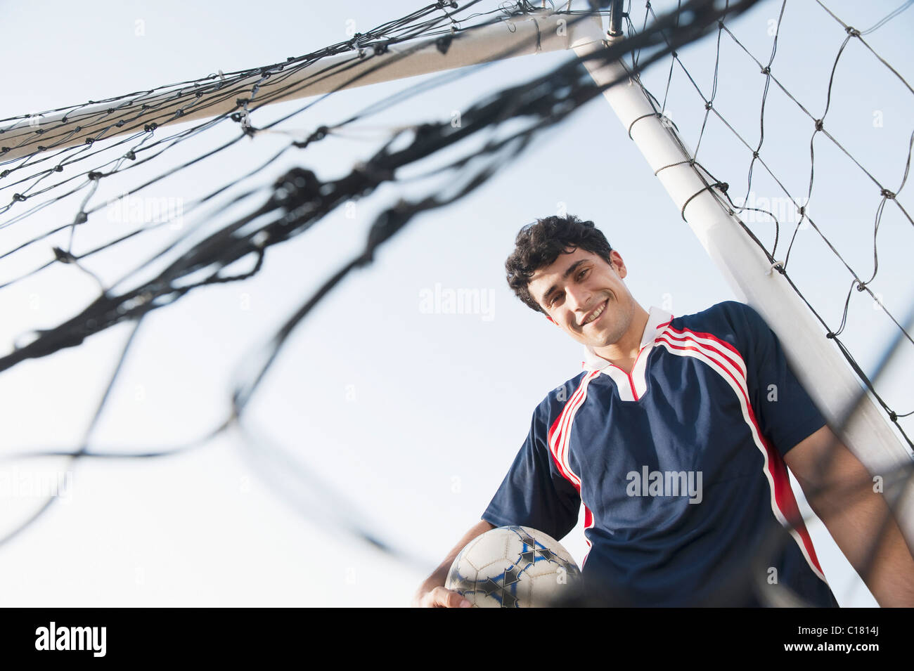 Soccer player holding a soccer ball behind the net Stock Photo - Alamy