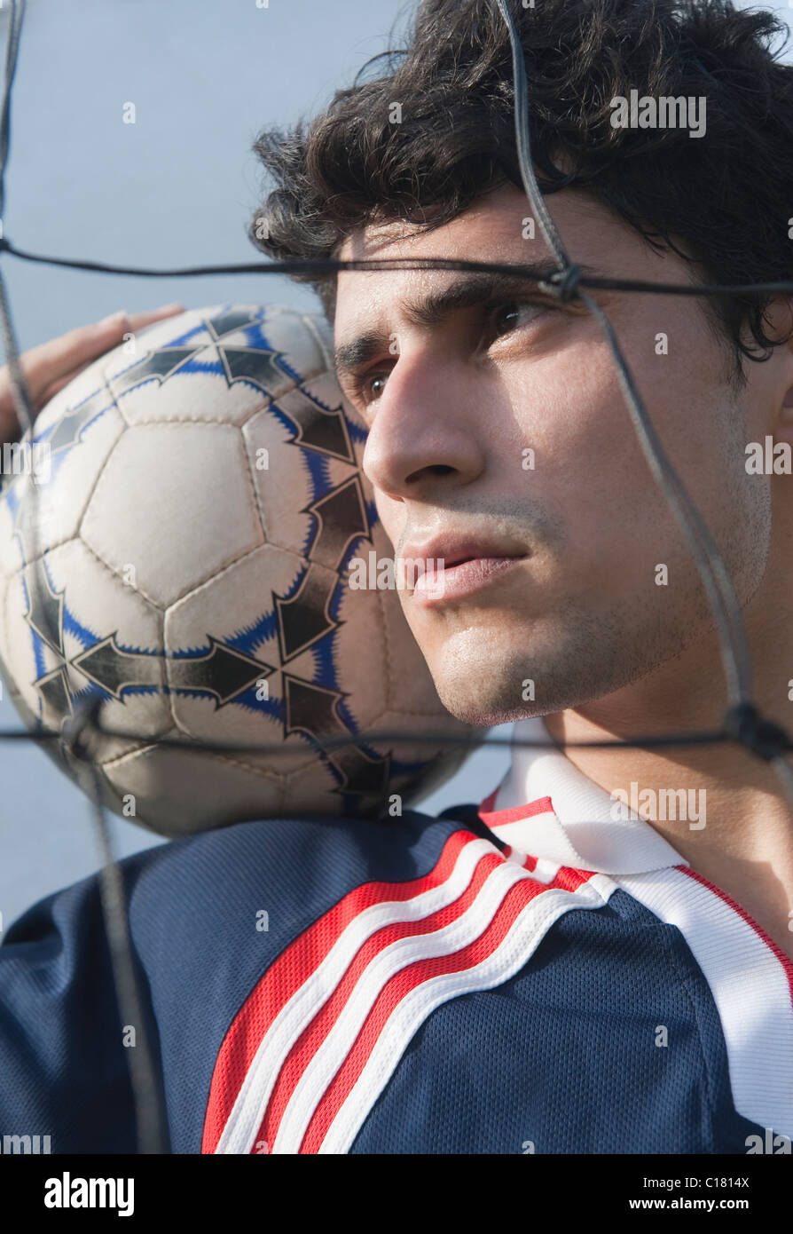Soccer player holding a soccer ball behind the net Stock Photo - Alamy