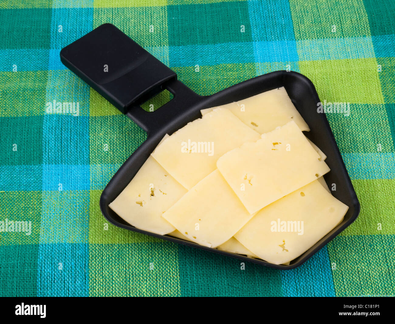 Raclette pan with edam cheese on colorful tablecloth Stock Photo - Alamy