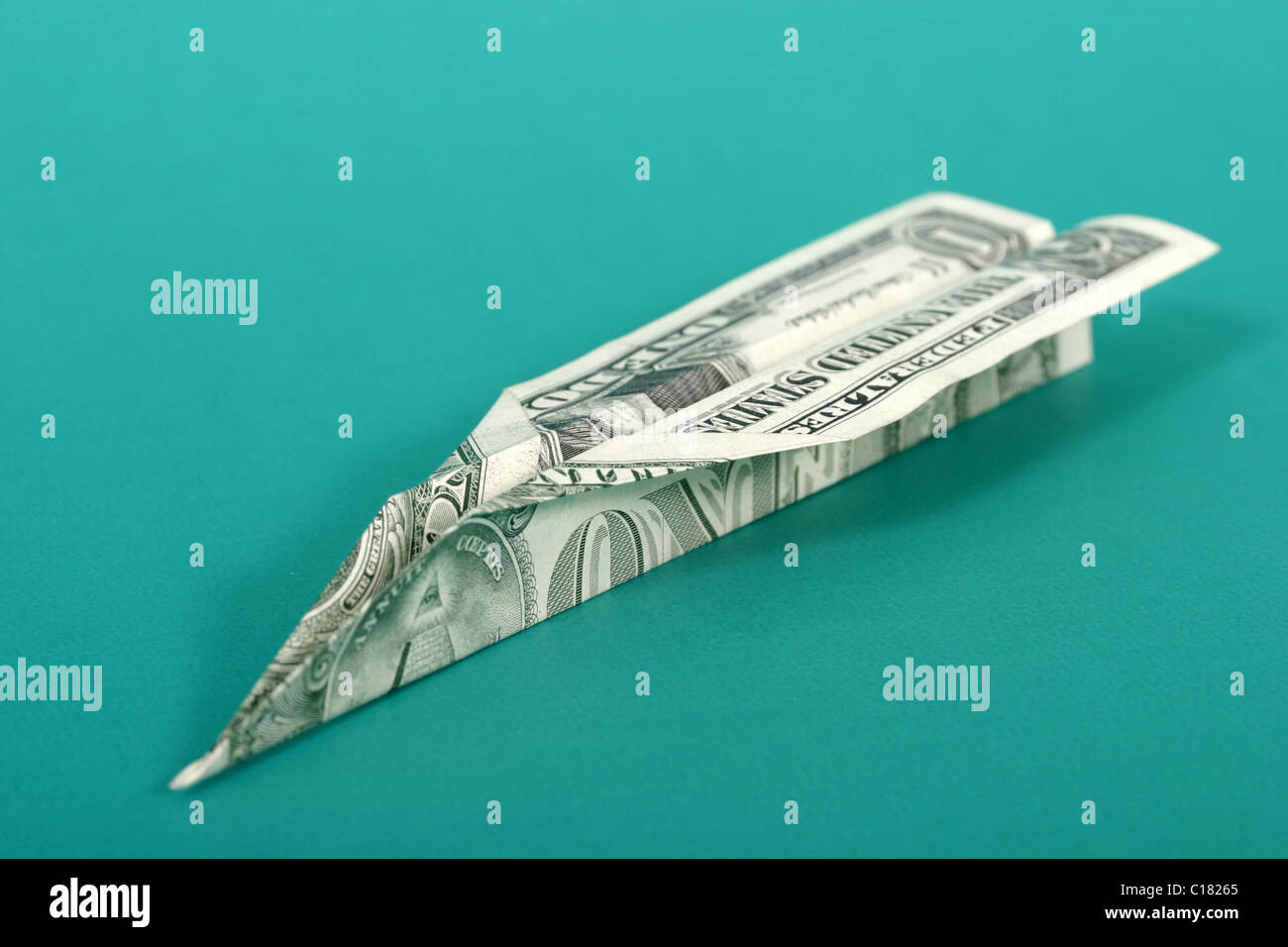 US dollar bill folded into a paper airplane on a green background Stock ...