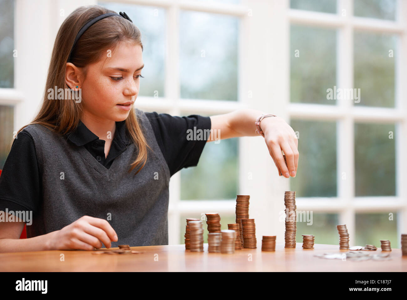Girl counting piles of money Stock Photo - Alamy