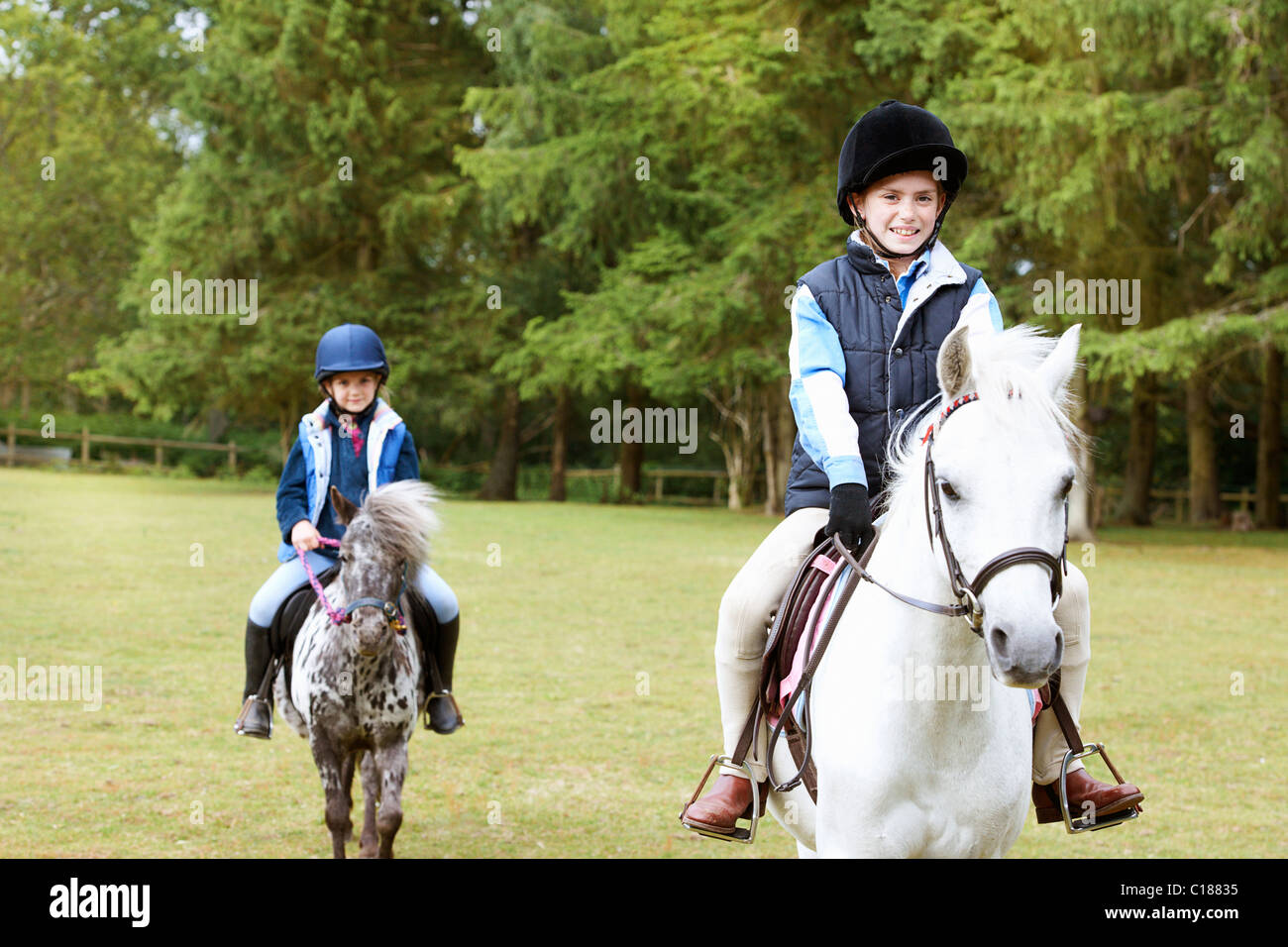 Two girls riding their ponies Stock Photo - Alamy