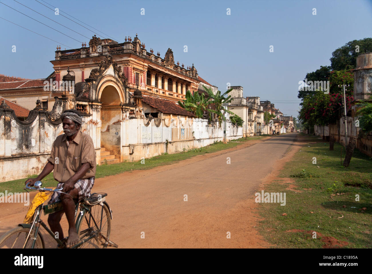 Man cycling on a village road with old buildings Stock Photo - Alamy