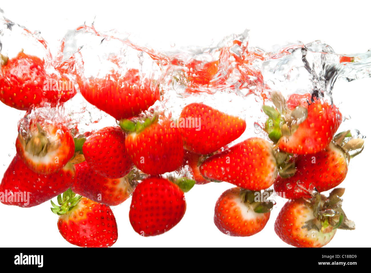 Photo of strawberries falling into water against a white background ...