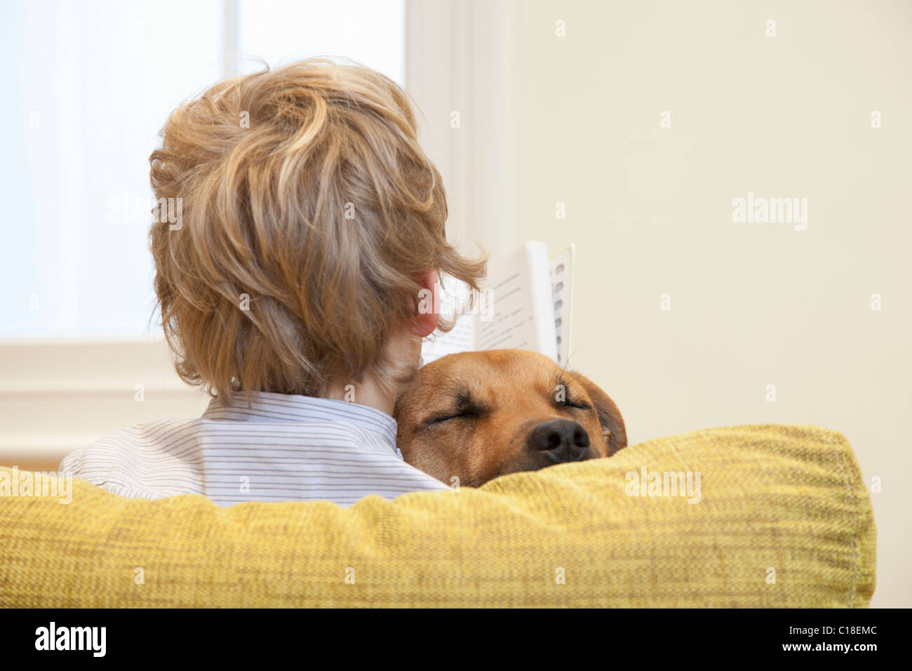 Boy reading whilst cuddling dog Stock Photo - Alamy