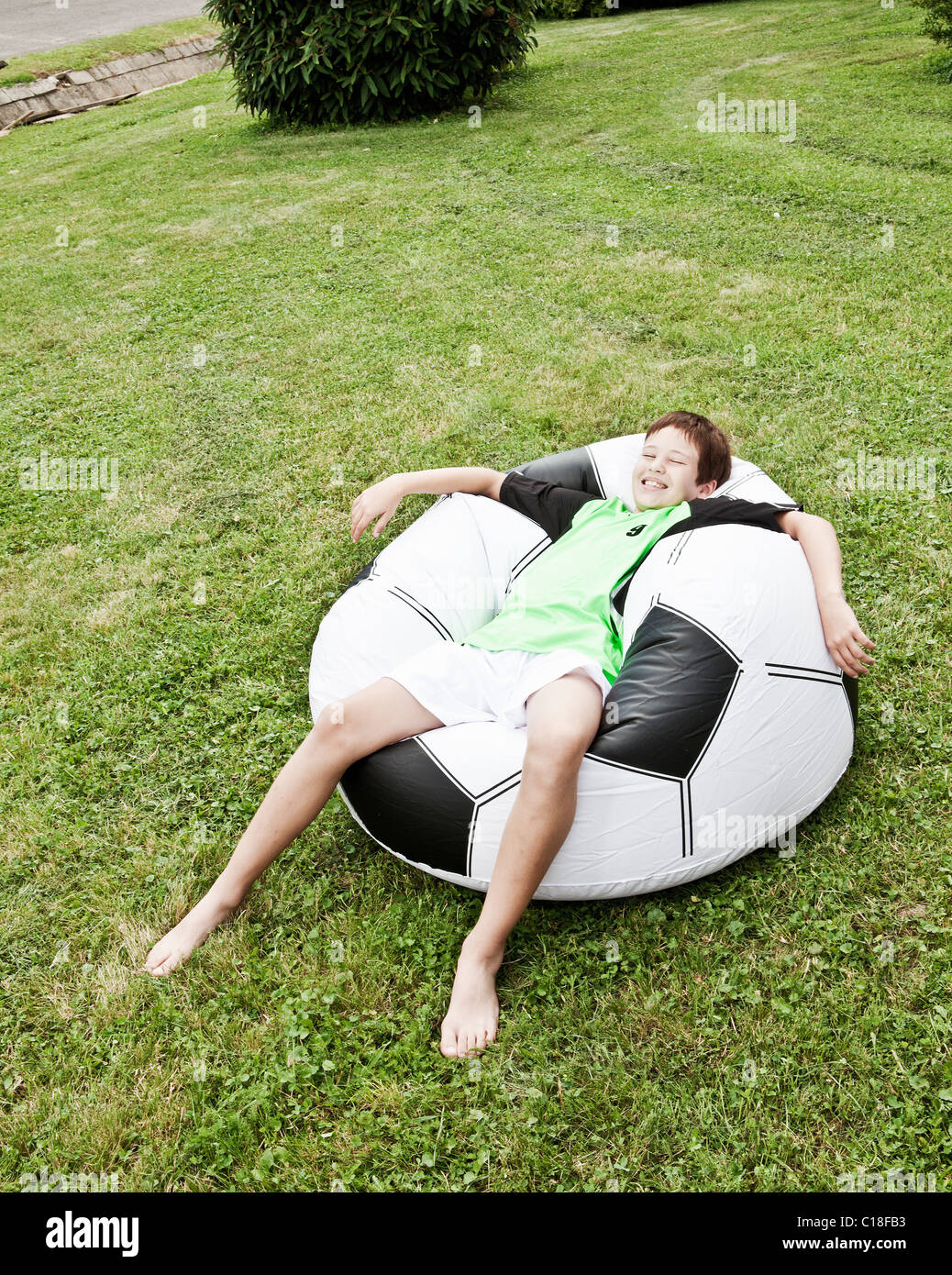 Boy relaxing on inflated giant football Stock Photo - Alamy