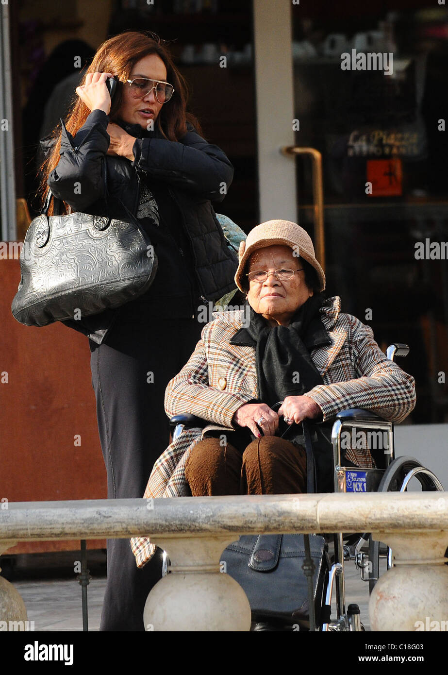 Tia Carrere with her mother fumbles with shopping bags to answer her ...