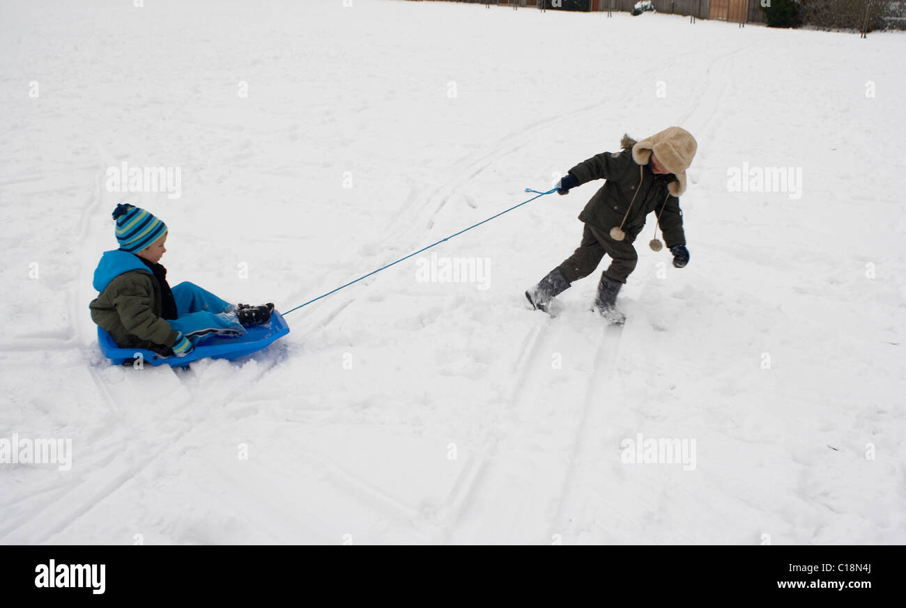 Boy pulling his friend on a sledge Stock Photo - Alamy