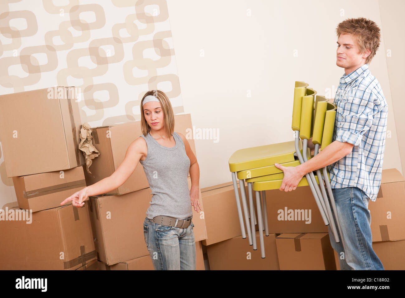 Moving house: Man and woman with box and chair, woman pointing Stock ...