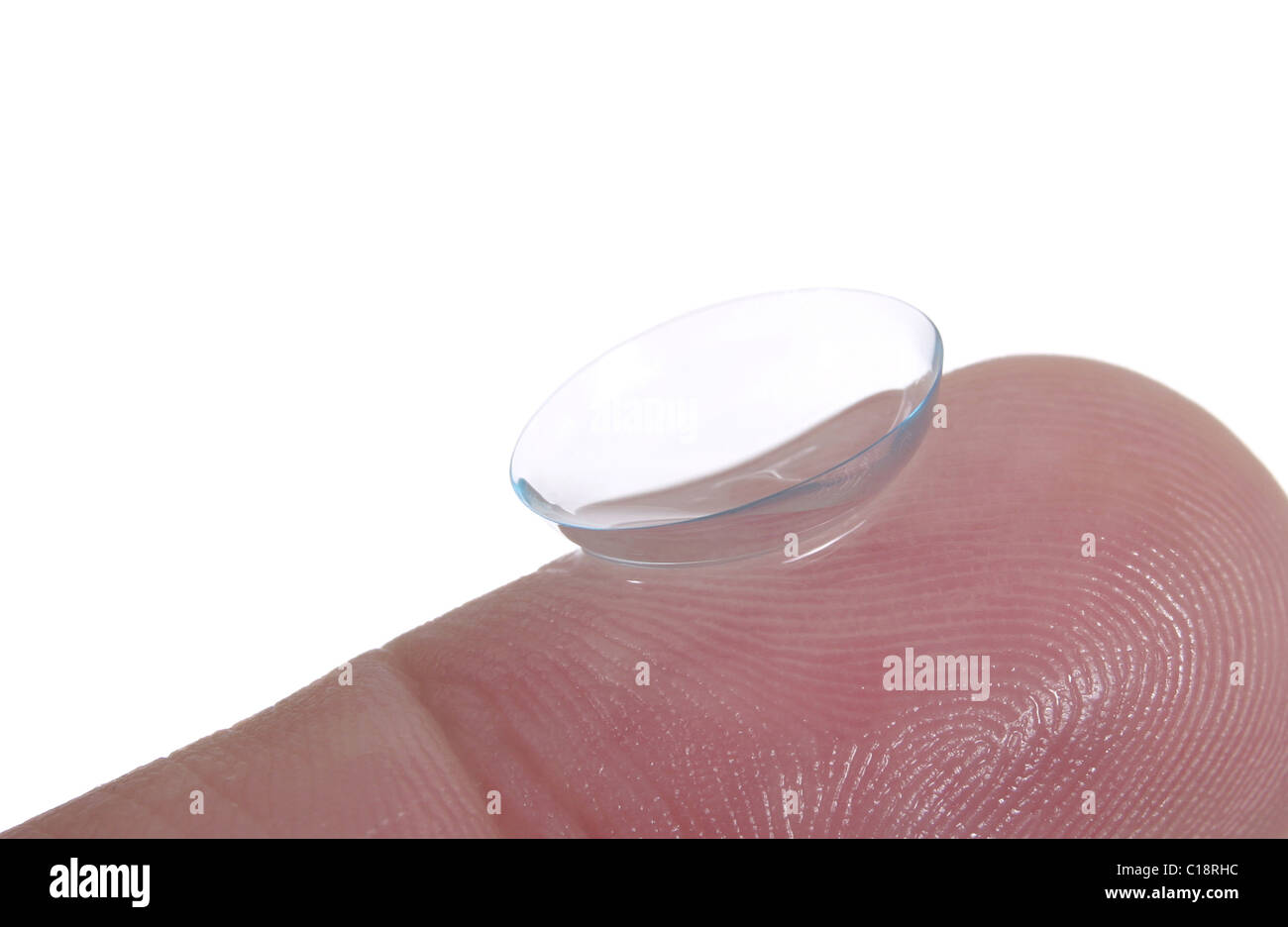 Closeup view of a contact lens on a finger with a white background ...