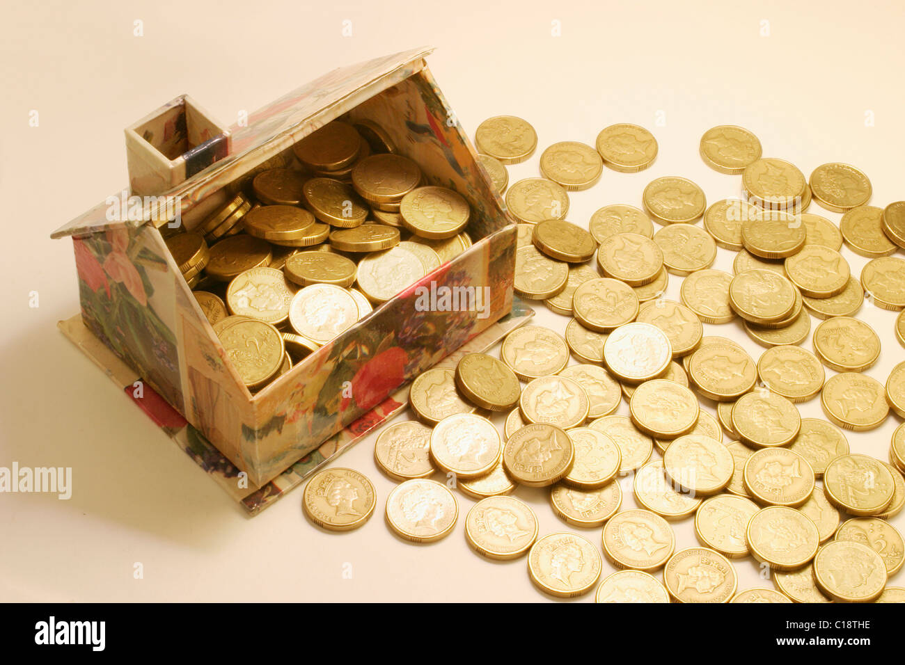 Toy house filled with coins, excess coins aside Stock Photo - Alamy