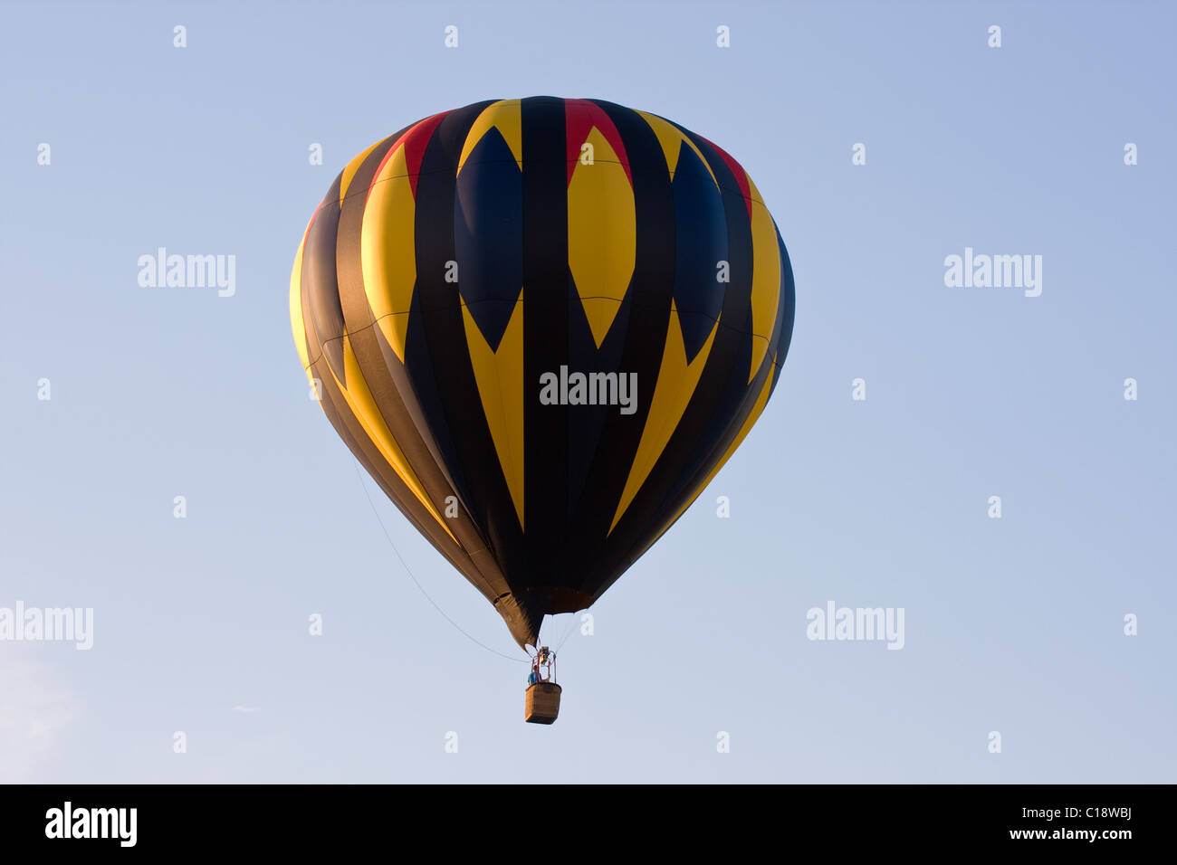 A colorful hot air balloon at a festival is suspended in mid-air on a ...