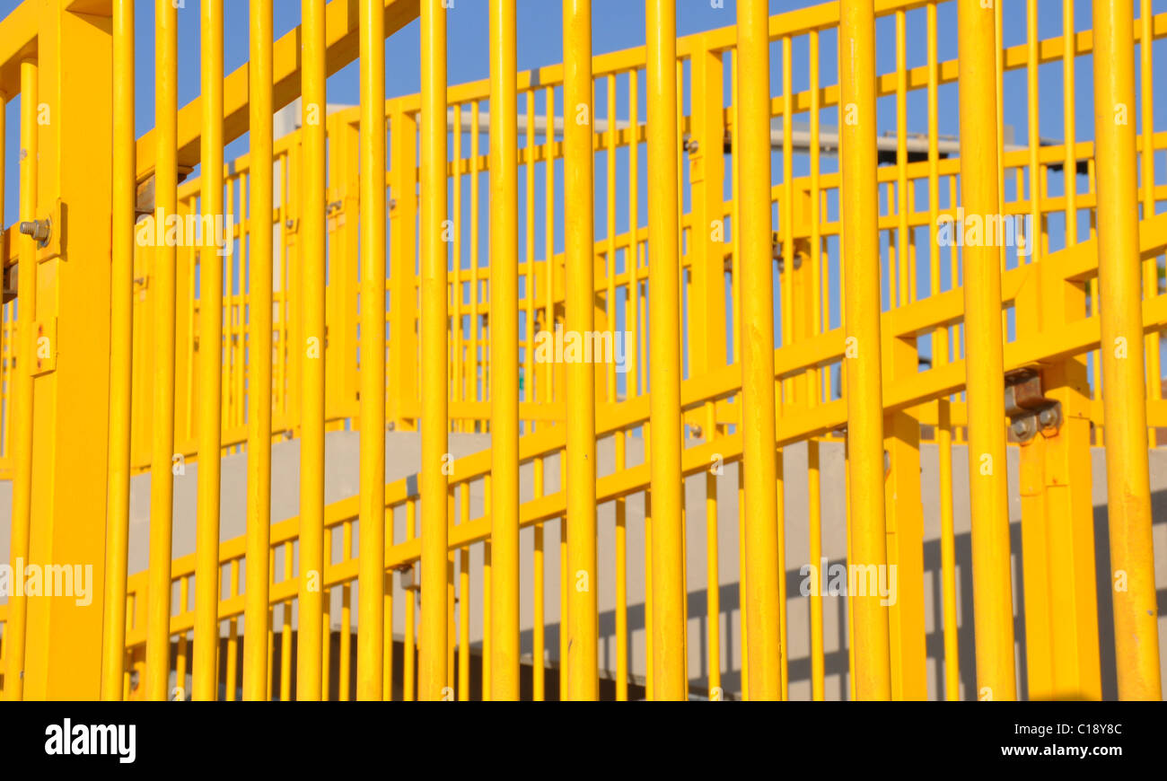 Pattern of bright yellow vertical stair railing against a blue sky ...