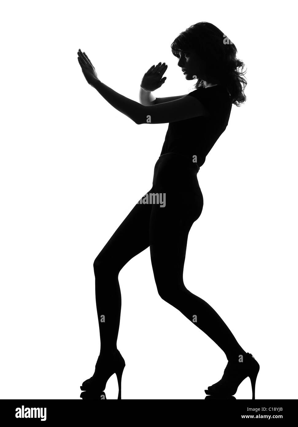 full length silhouette in shadow of a young woman fight karate self ...