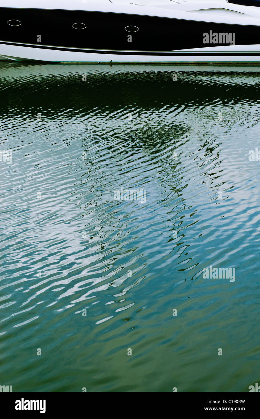 The colorful pattern of light reflected on a water surface with a boat ...