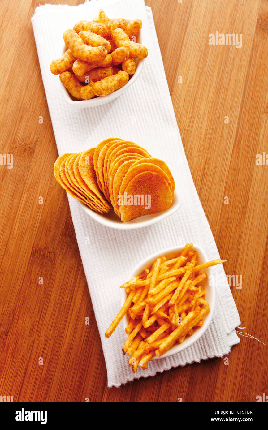 Various spiced snacks in bowls on a table, peanut flips, crisps, potato ...