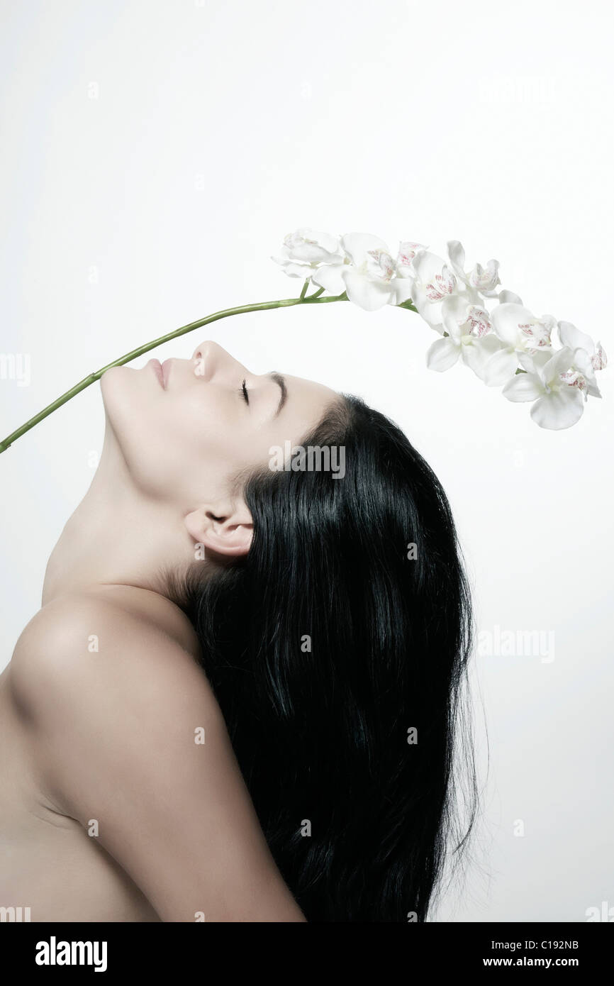 Dark haired young woman stretching under flower blossoms, portrait ...