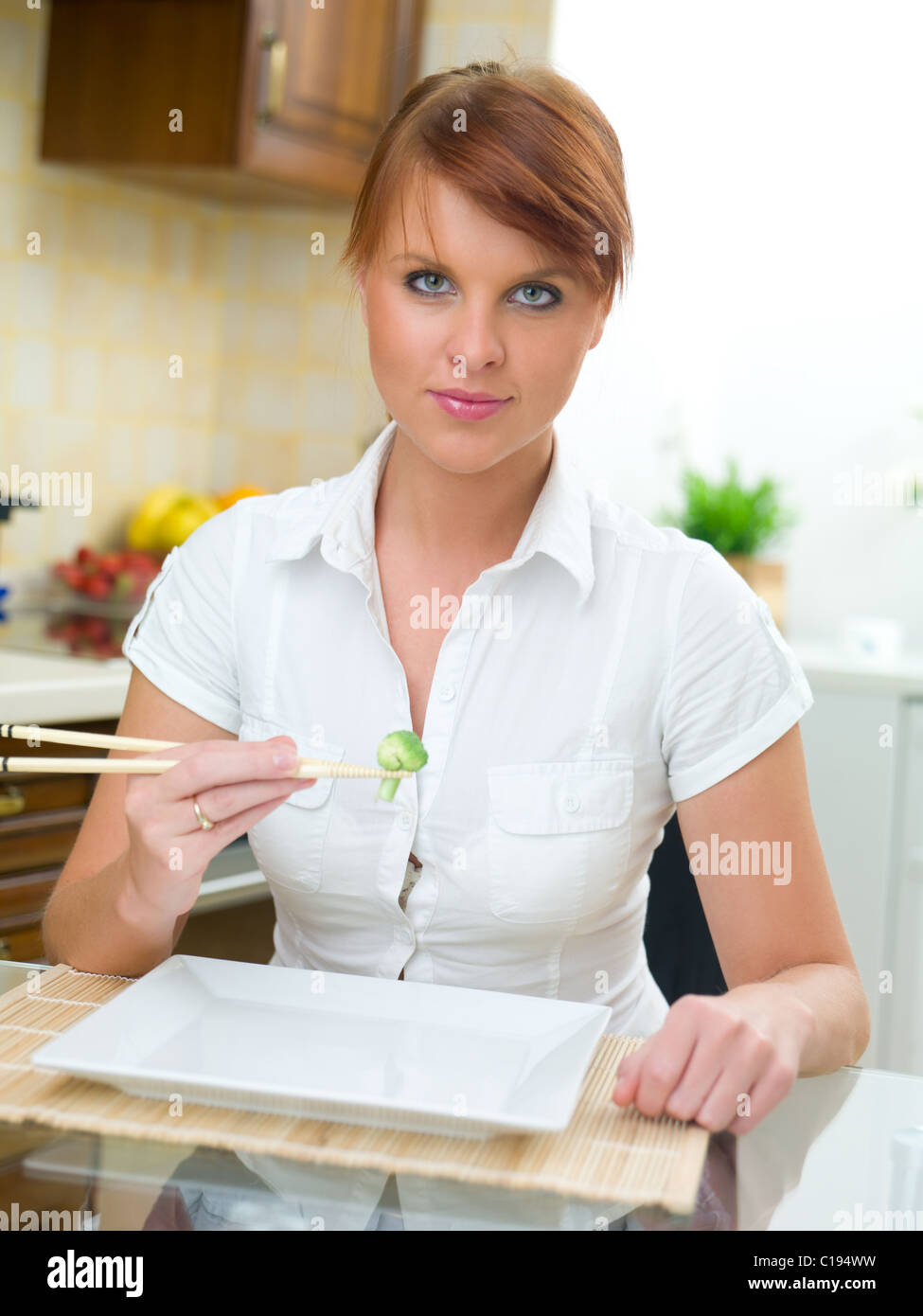Beautiful woman in kitchen eating using chopsticks Stock Photo - Alamy
