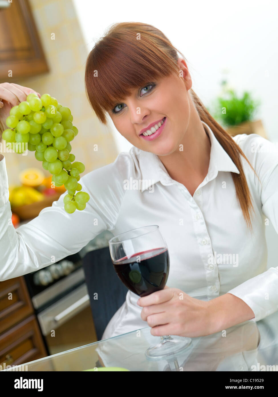 Beautiful woman in kitchen drinking red wine Stock Photo - Alamy