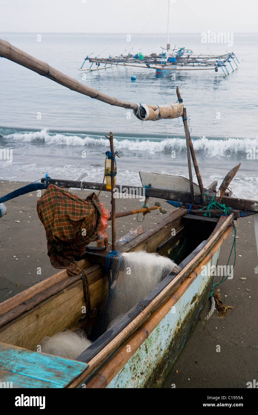 A traditional outrigger fishing boat, called a jukung, on the beach in ...