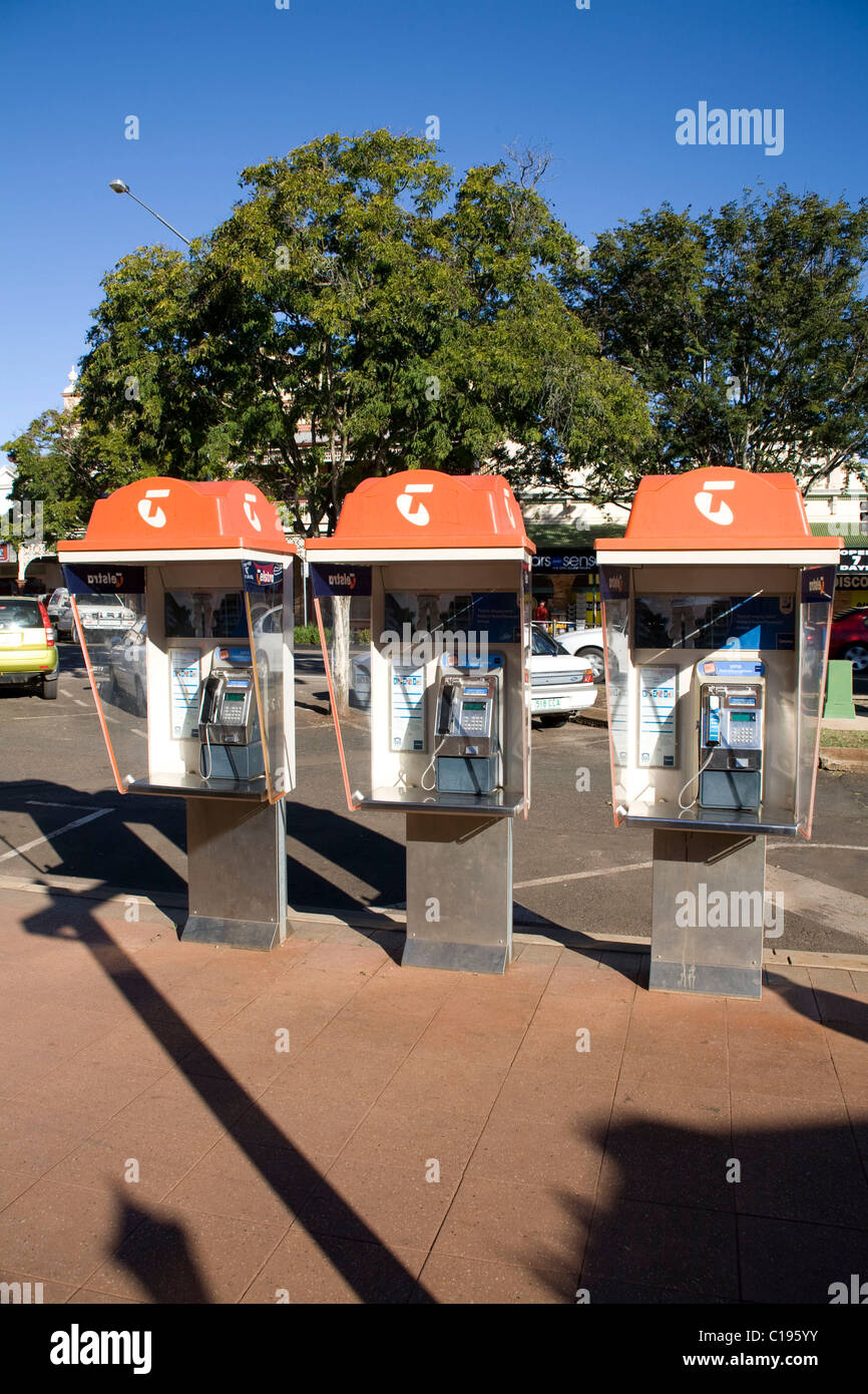A row of payphones with orange hoods in a street setting under a clear ...