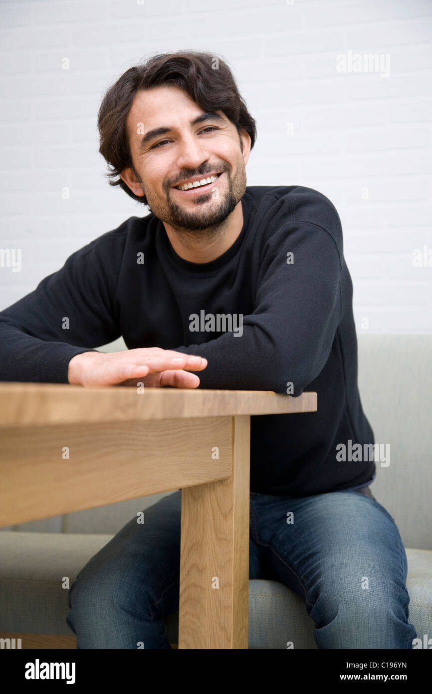 Man sitting at a wooden table Stock Photo - Alamy