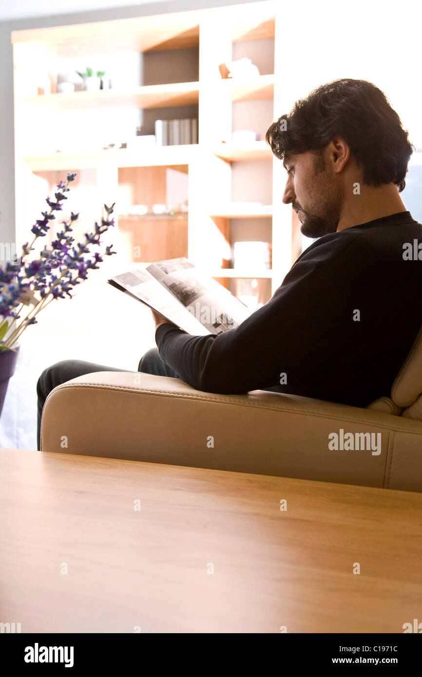 Man sitting comfortably on a sofa, reading Stock Photo - Alamy