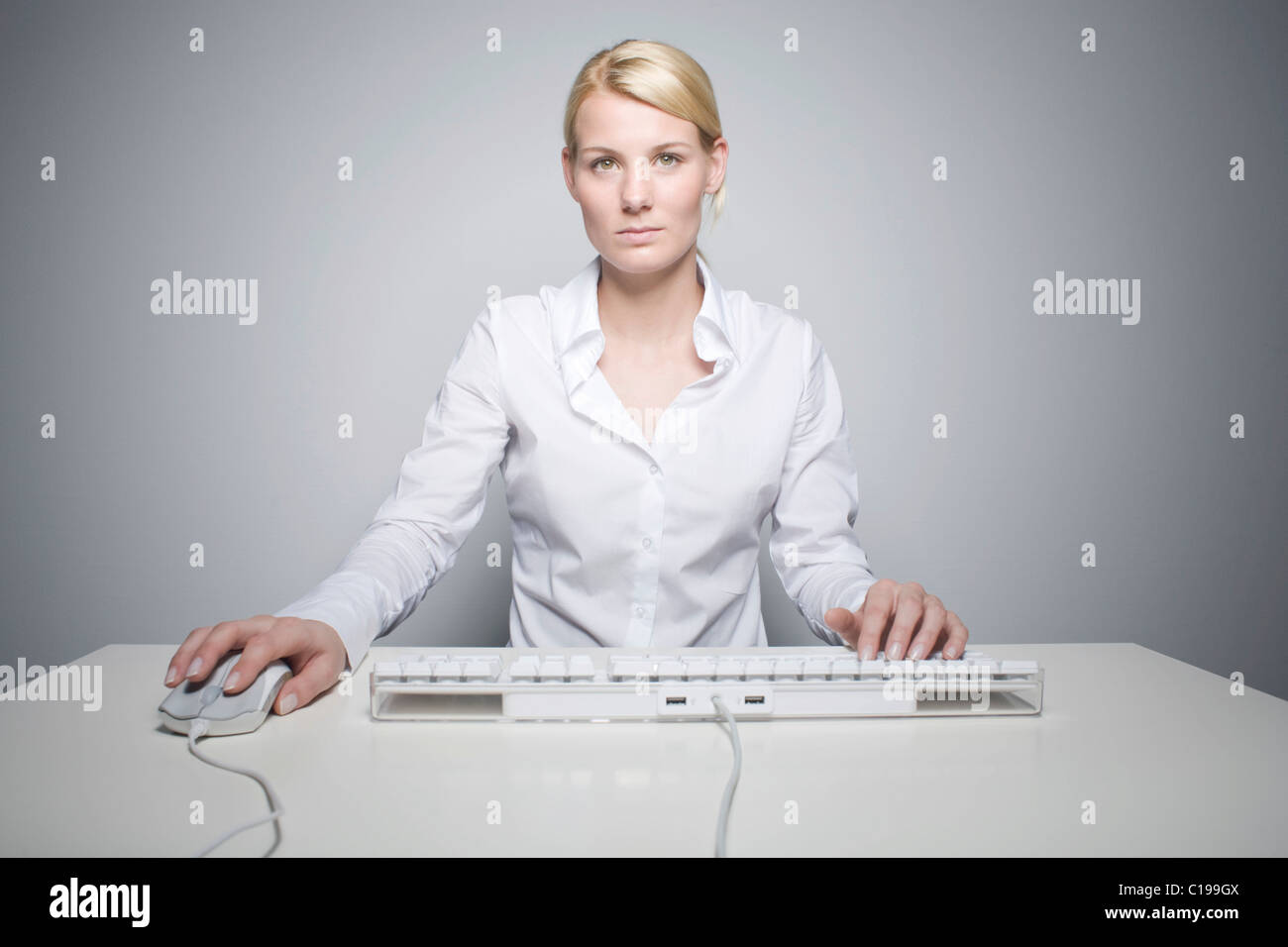 Young blond woman using a computer keyboard and mouse Stock Photo - Alamy