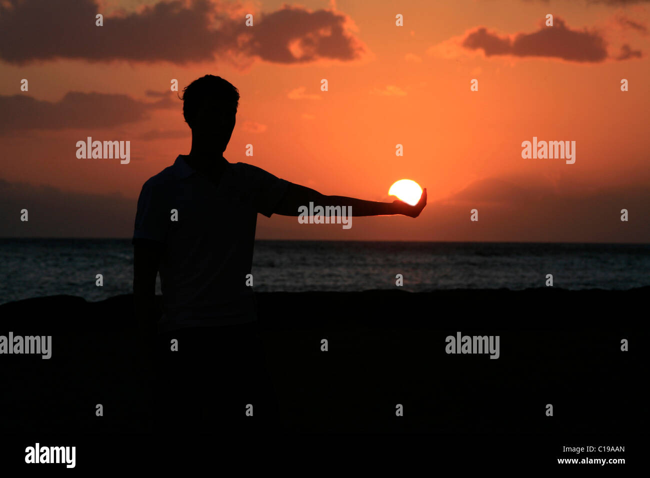 Man holding the setting sun in his hand, Kihei, South Maui, Hawaii, USA ...