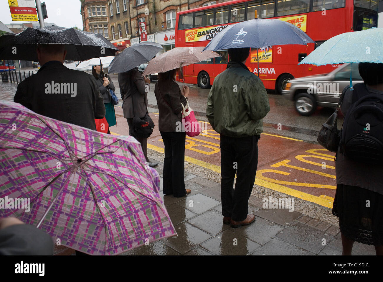 Morning London commuters queue in the rain for a red bus Stock Photo ...