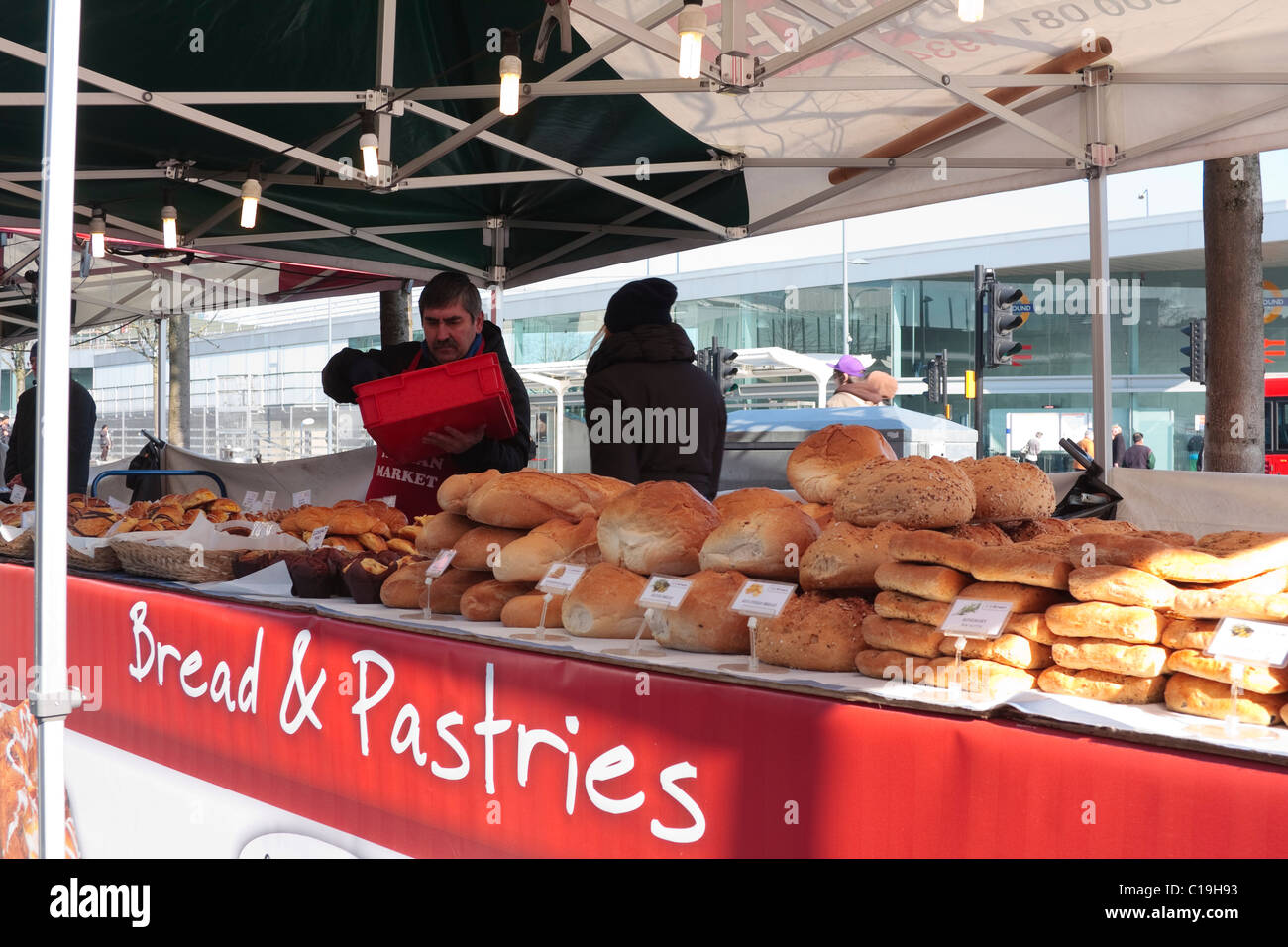 A man selling fresh bread adds more bread to his market stall Stock ...